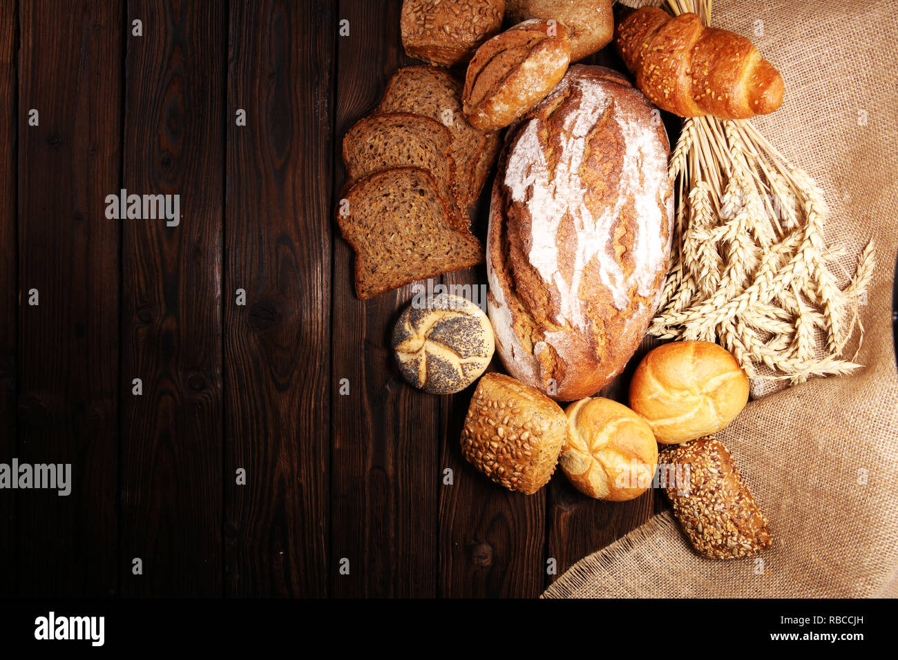 Different kinds of bread and bread rolls on board from above. Kitchen ...
