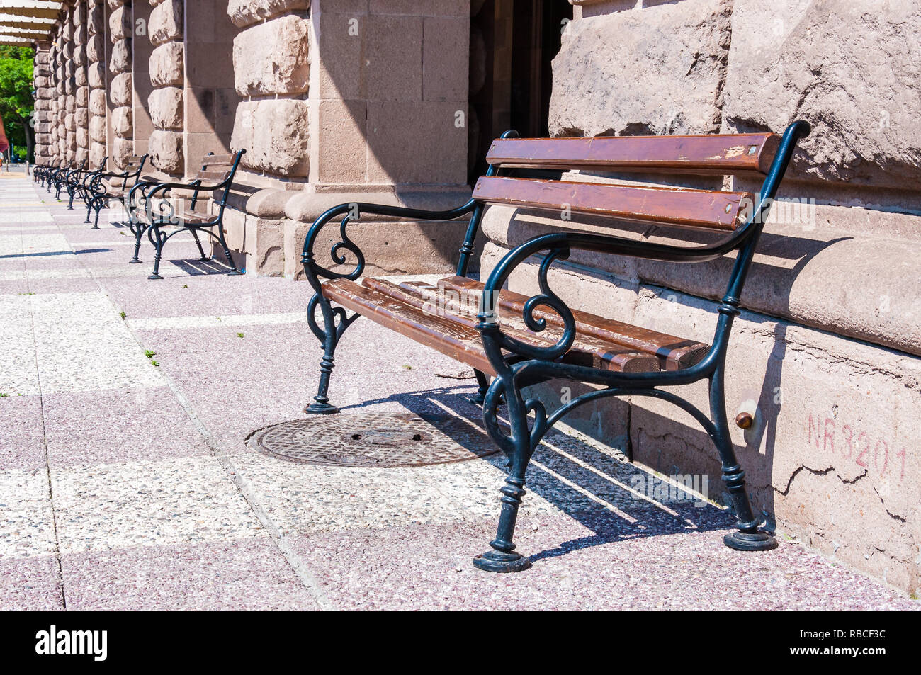 Outdoor street benches made of curved forged metal and wood standing in ...