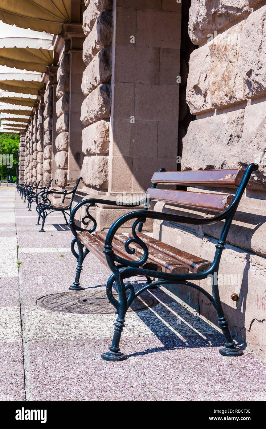Outdoor street benches made of curved forged metal and wood standing in ...
