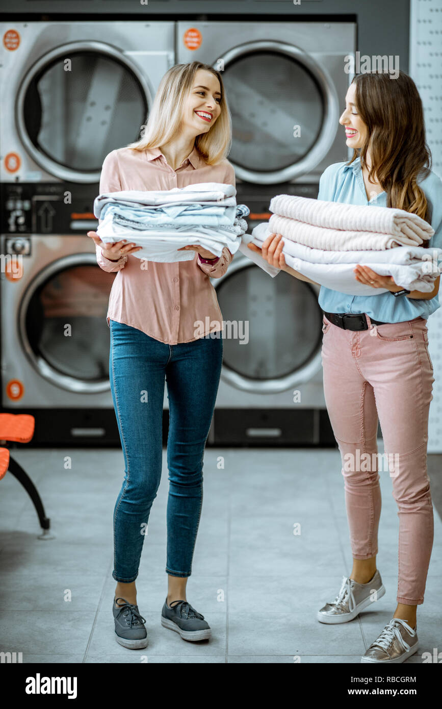 Two young women standing together with clean clothes in the self ...