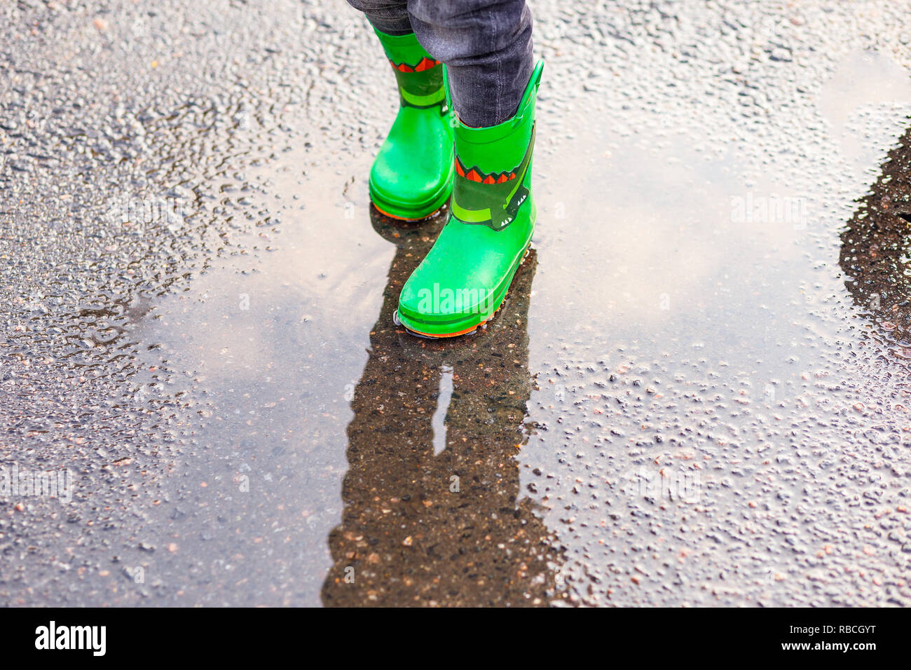 Green rubber boots and a puddle. Childhood Stock Photo - Alamy