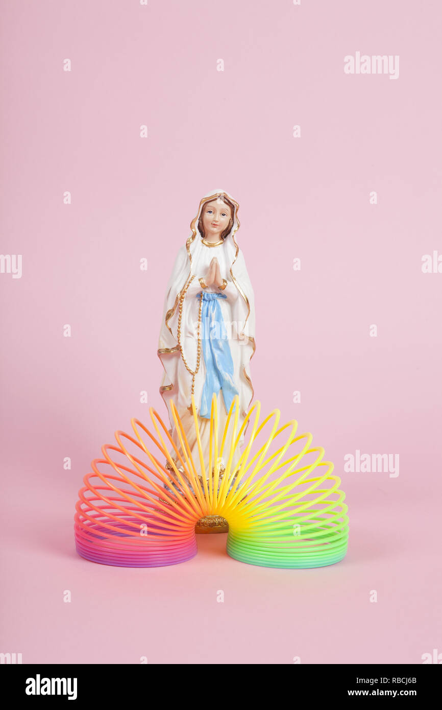 Icon of the Virgin Mary of Lourdes placed near rainbow spring on a pink ...