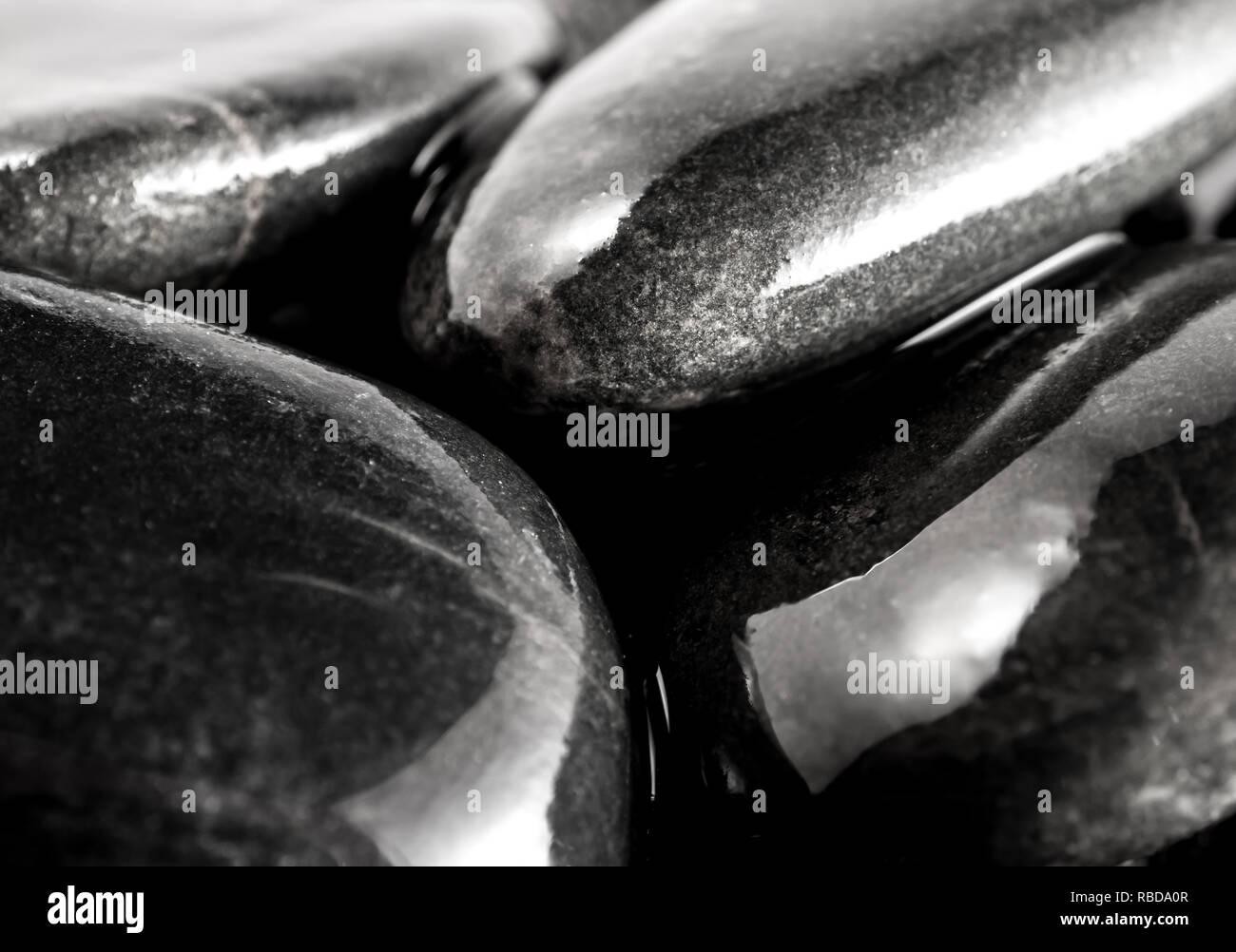 Glossy surface of round black stone on ground beside the waterfall ...