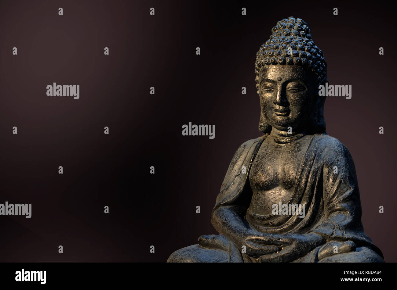 Buddha statue sitting in meditation pose against deep dark background ...