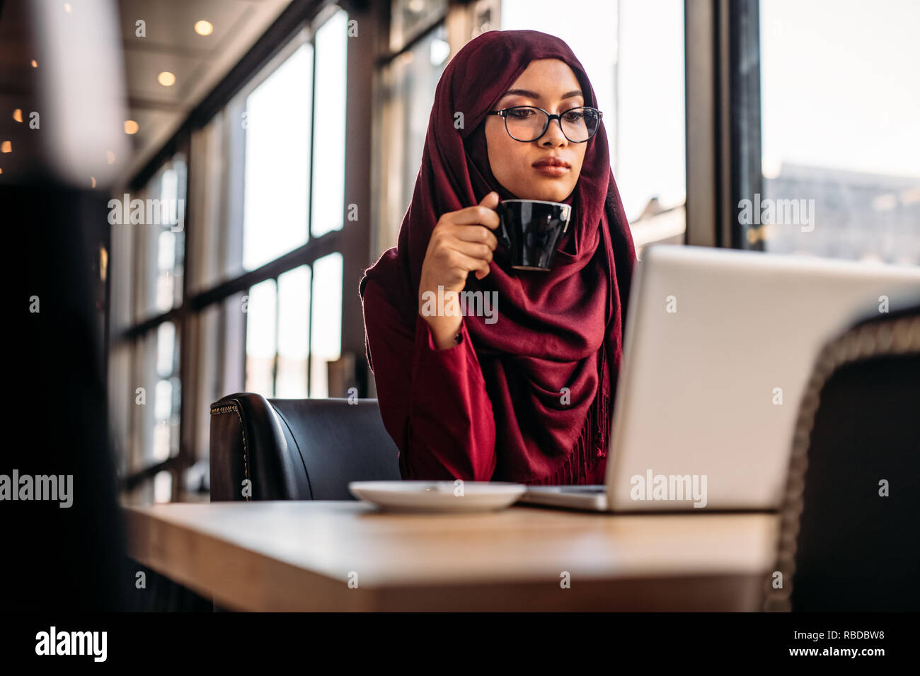 Muslim woman working at a cafe and using laptop computer. Female in ...