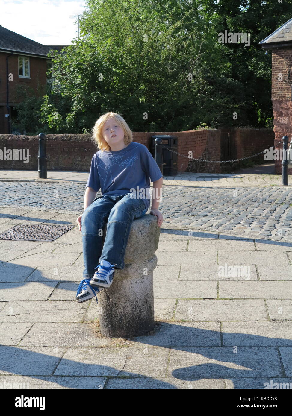 young boy sitting on a stone pillar Stock Photo - Alamy