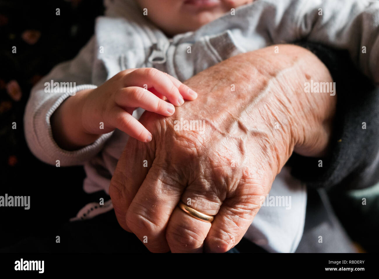small baby hand touching and caressing old grandmother hand with ...