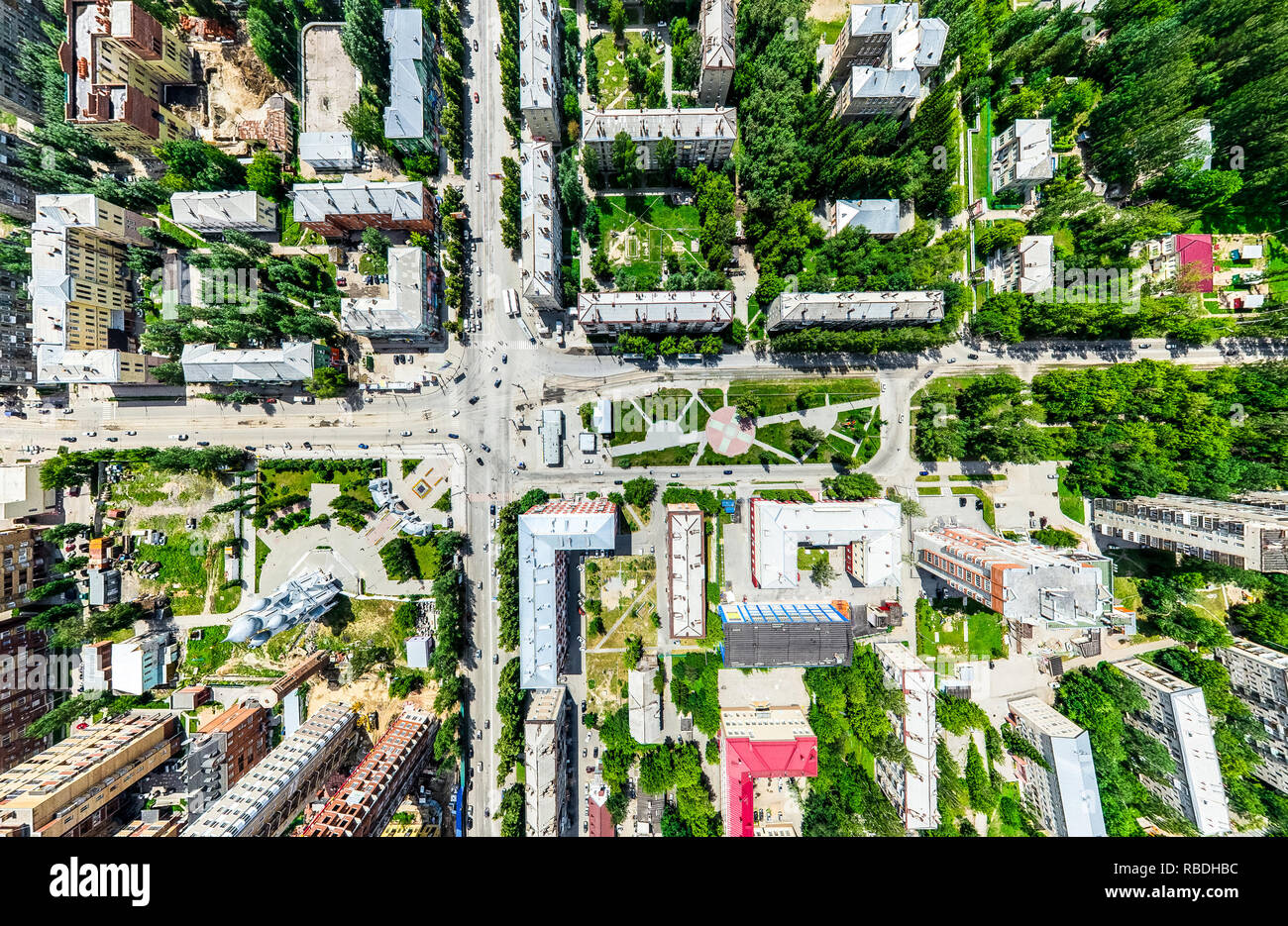 Aerial city view with crossroads and roads, houses, buildings, parks and parking lots. Sunny ...