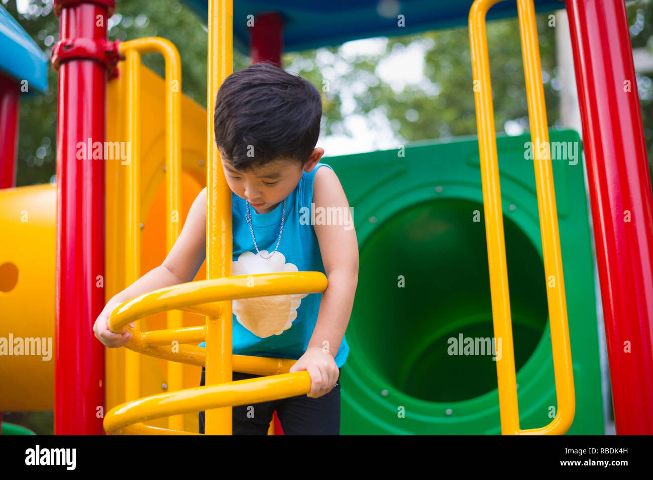 Active Asian Kid playing climbing metal spiral at school yard ...
