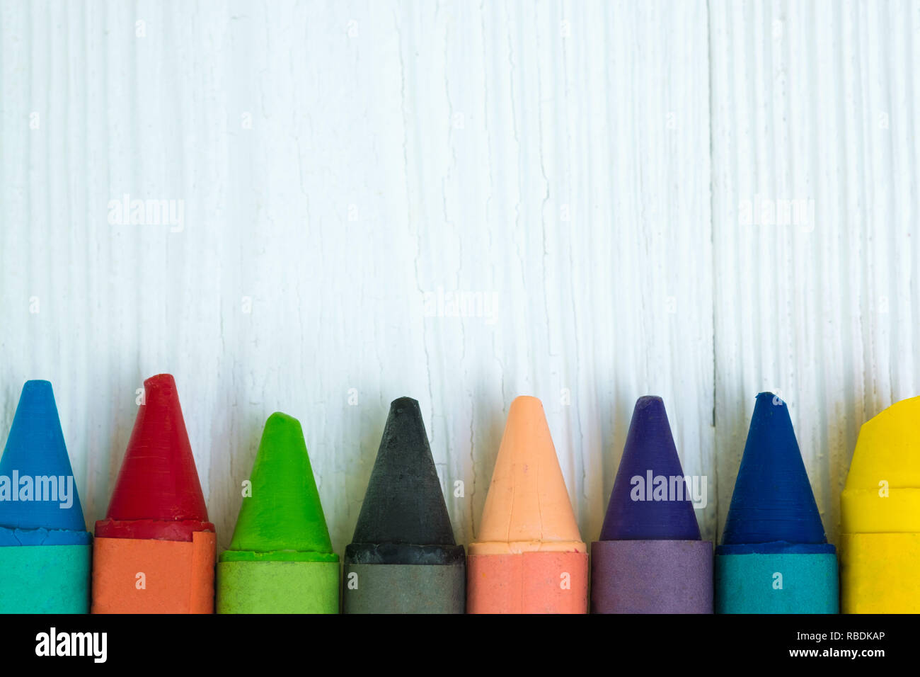 Colourful wax crayons pencils on white wood table with copy space for ...