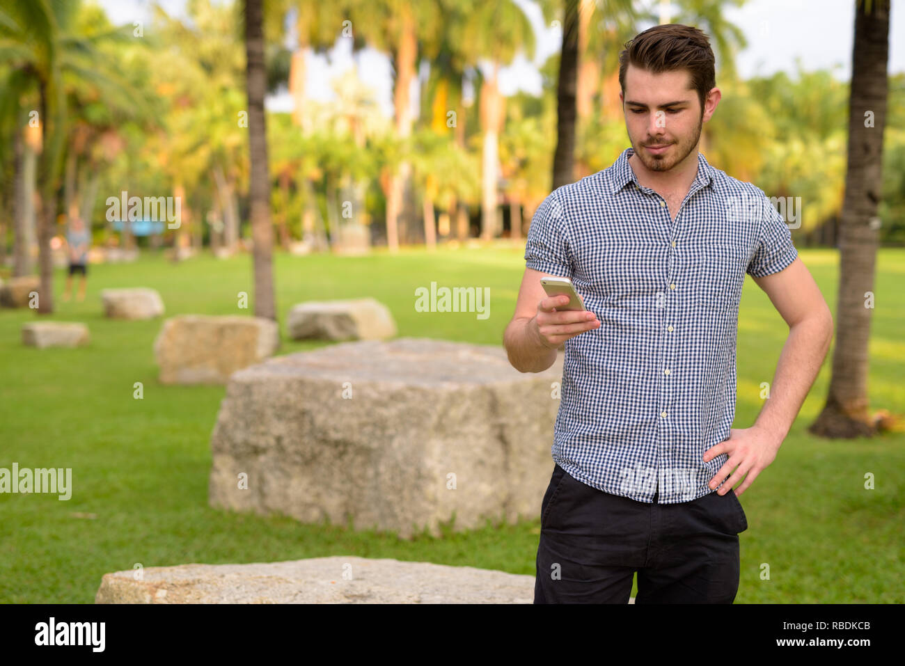 Happy man relaxing at the park while using mobile phone Stock Photo - Alamy