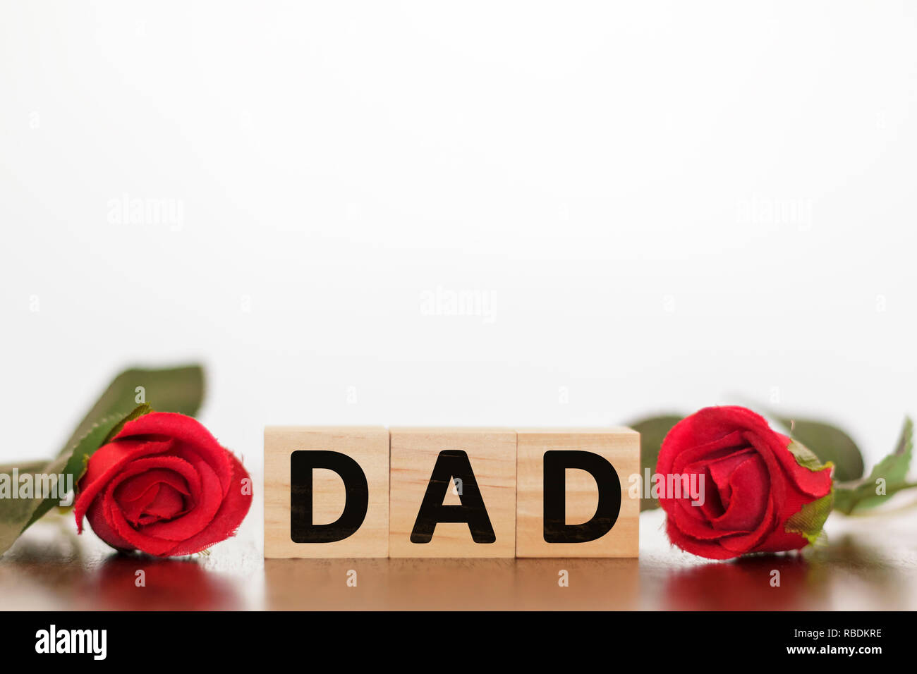 DAD word written on wooden cubes with red roses around. Father's day ...