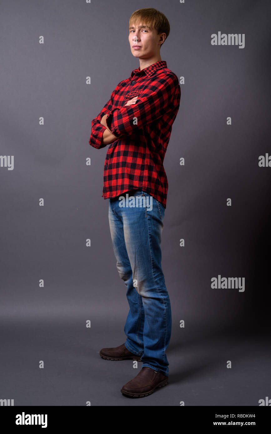 Full length portrait of young man standing against gray background ...