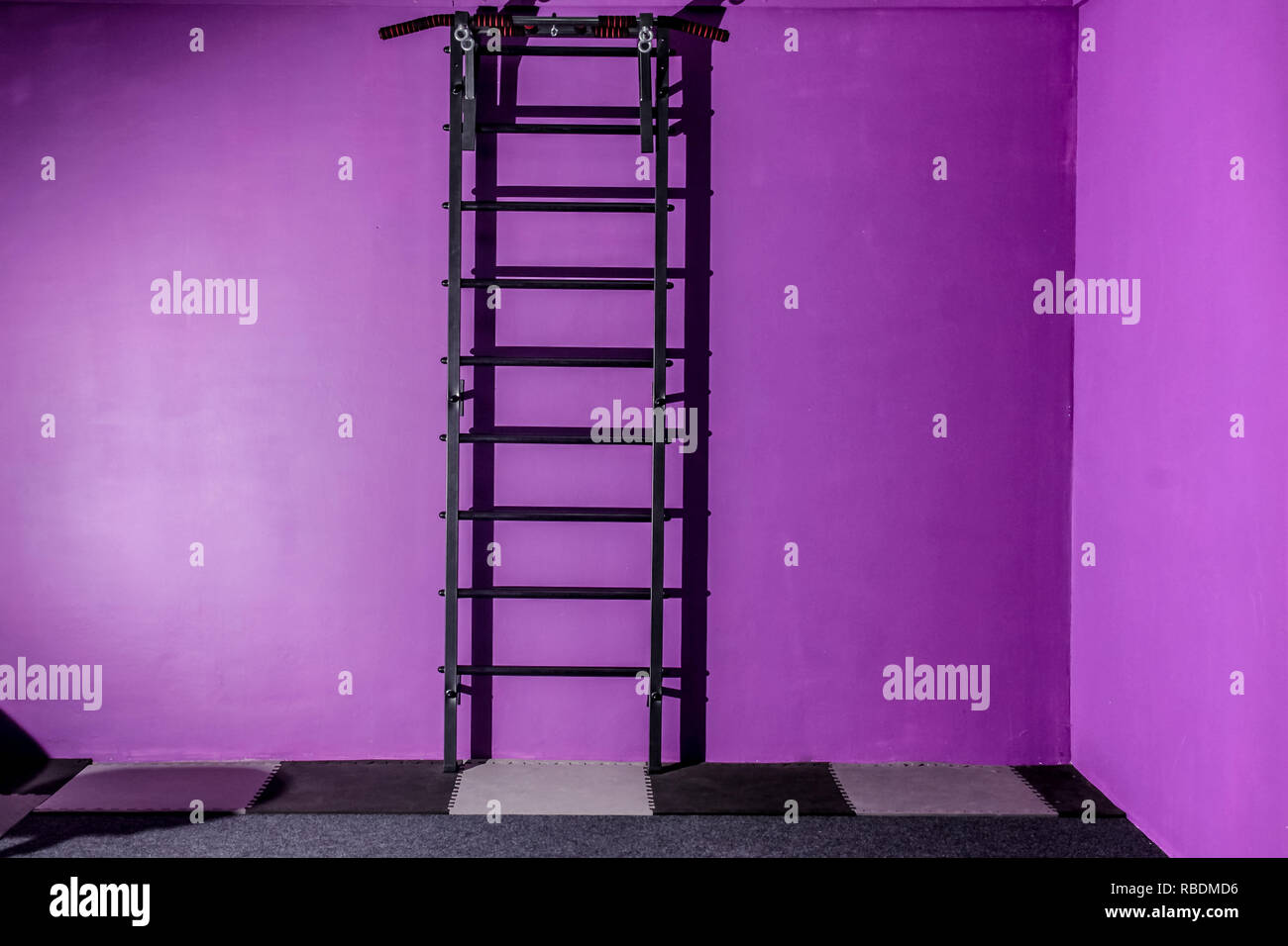 Empty gym fitness hall with sports equipment and a ladder on the wall ...