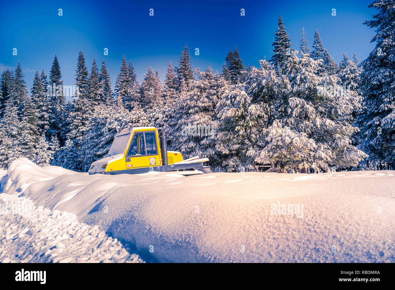 Yellow tractor crawler covered under snow on Icy country road in snowy ...