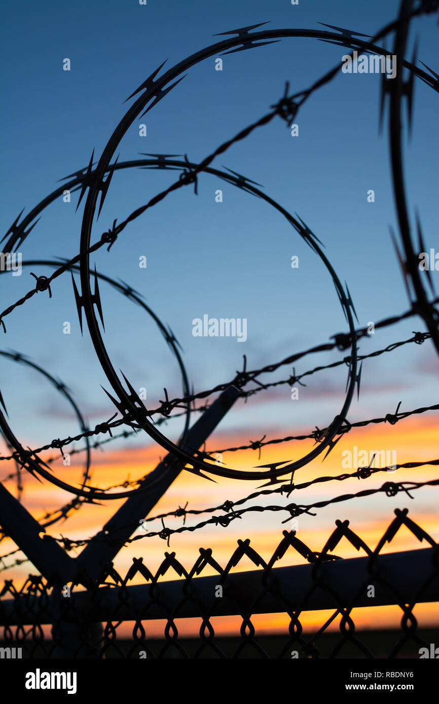 Dramatic sunset with chain link fence and razor wire silhouette Stock ...