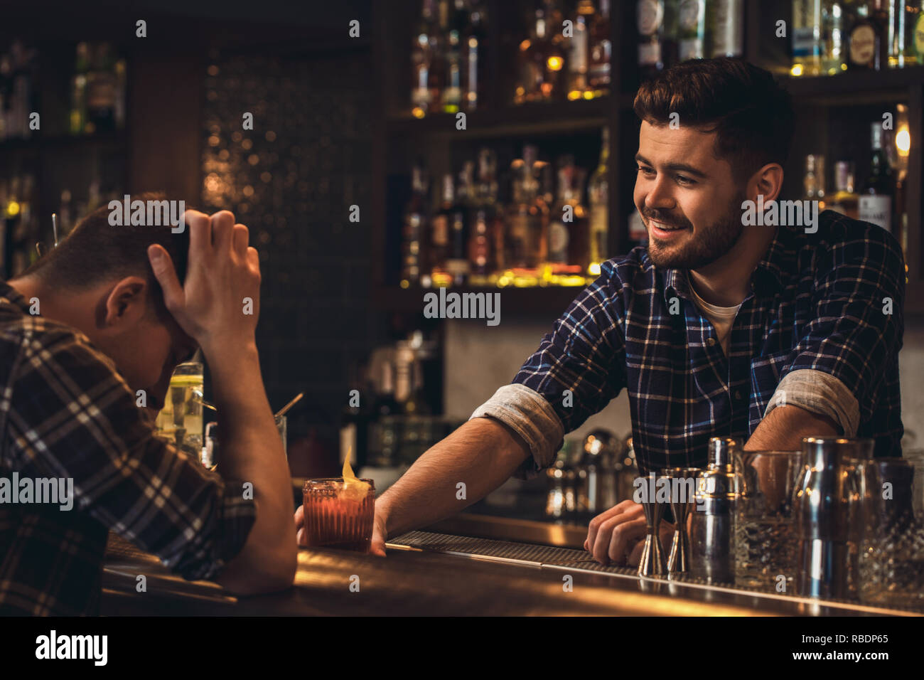 Young barman standing at bar counter serving cocktail smiling happy ...