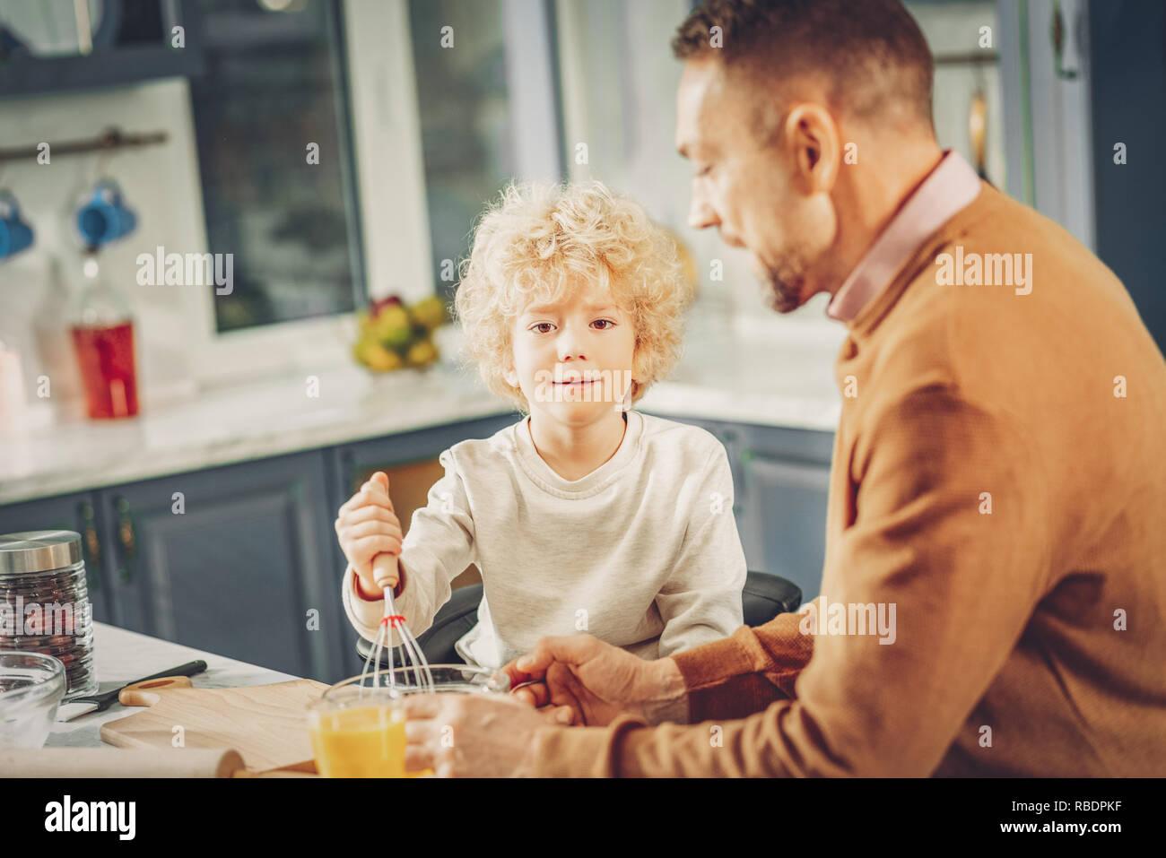 Real men. Appealing sincere man and boy cooking dishes and talking ...