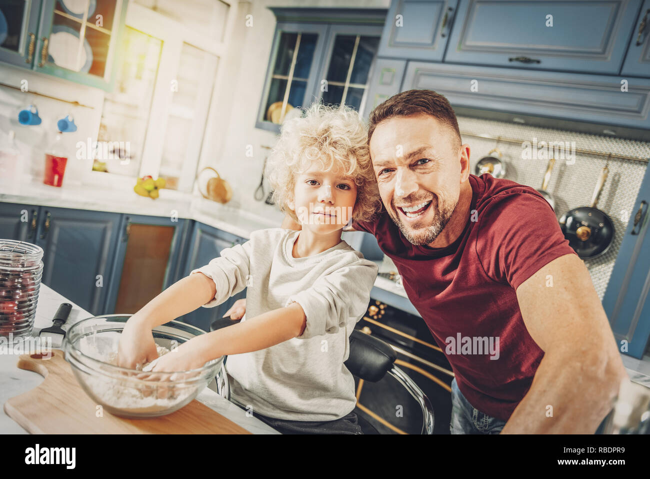 Faces in flour. Positive attractive boy making dough and man smiling to ...