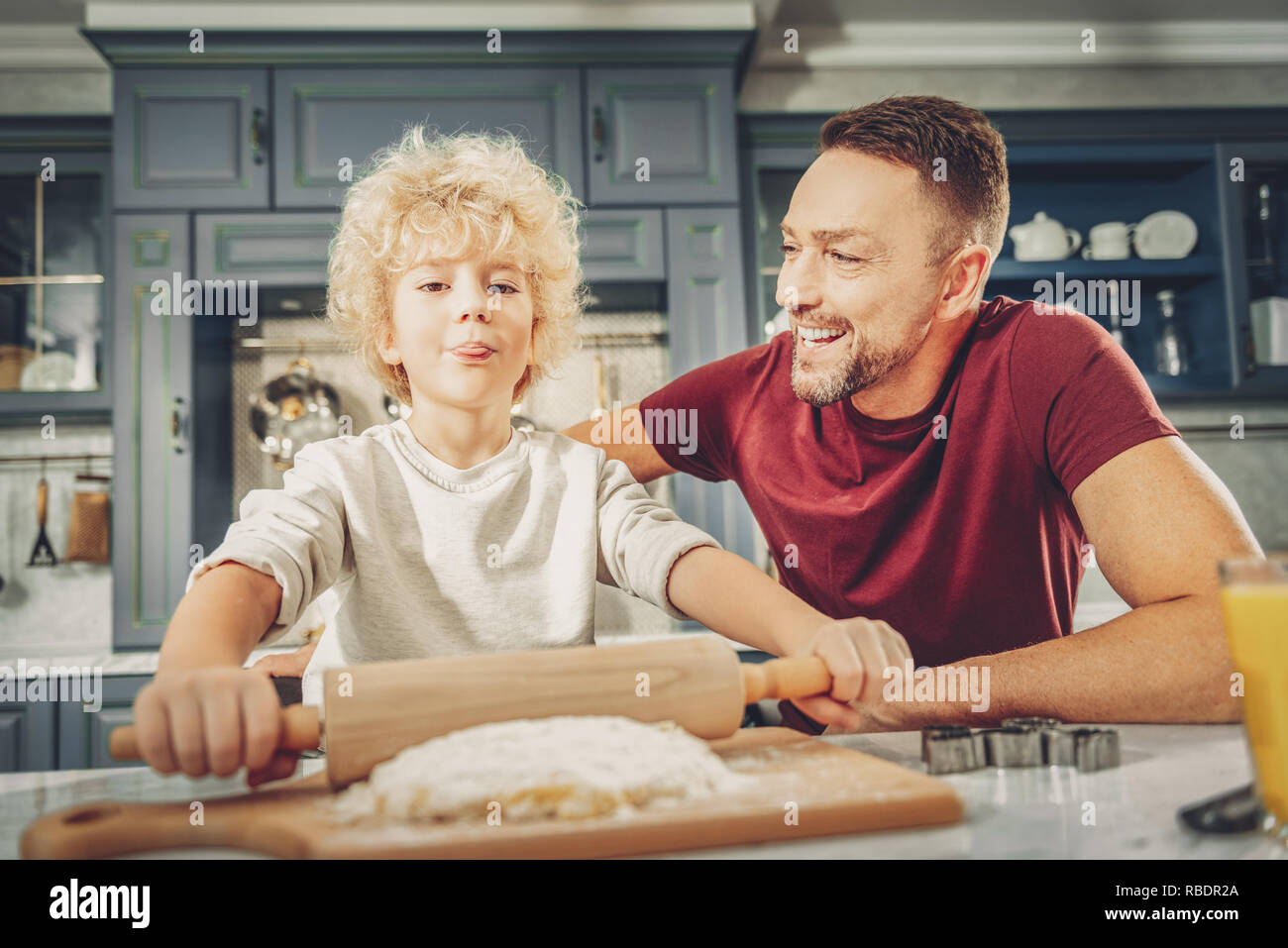 Classic rolling pin. Merry enthusiastic boy rolling up dough and ...