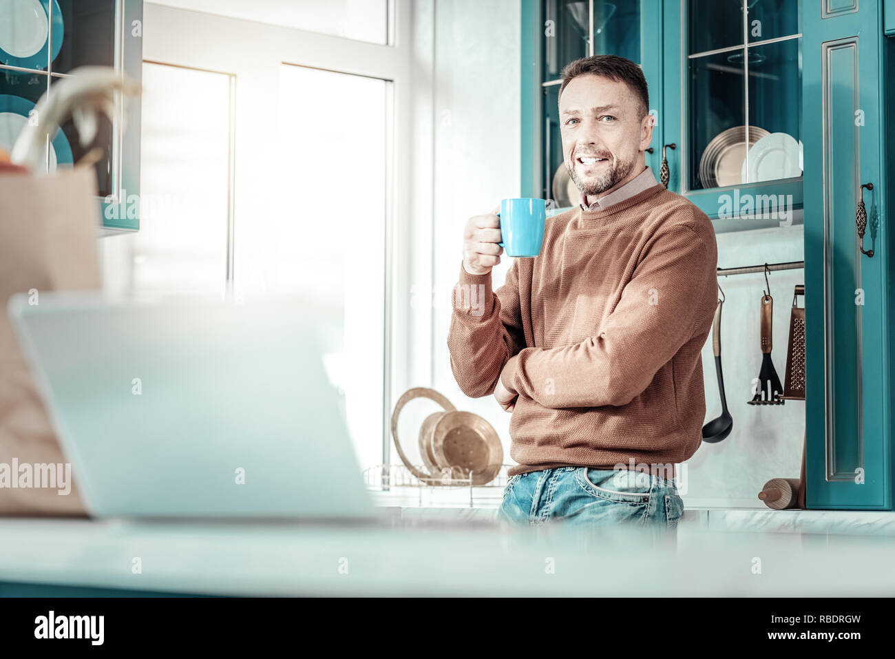 Time to relax. Pleased male person posing on camera while drinking tea ...