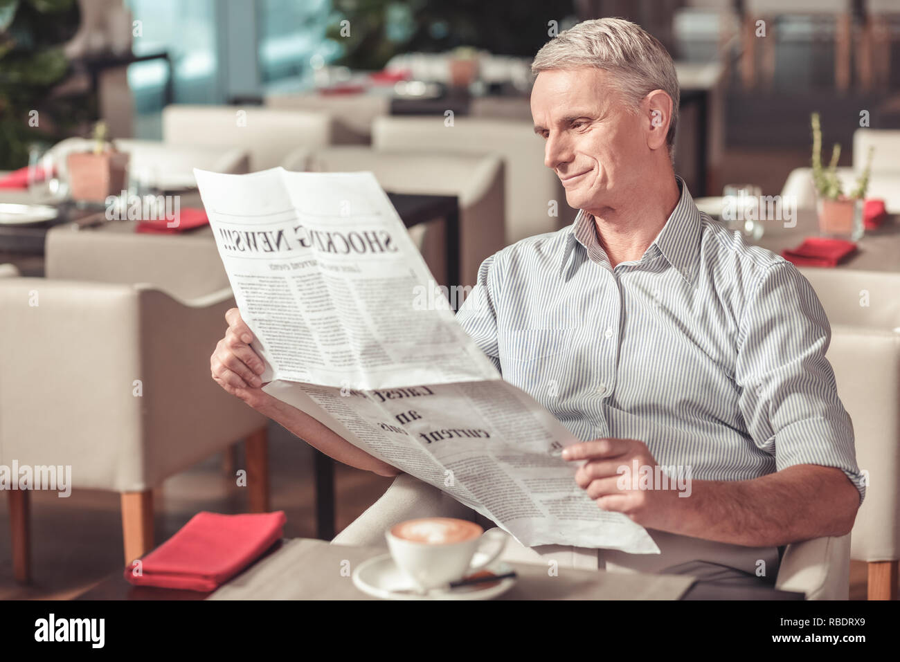 Good mood. Smiling pleasant pensioner sitting in a cozy cafe while ...