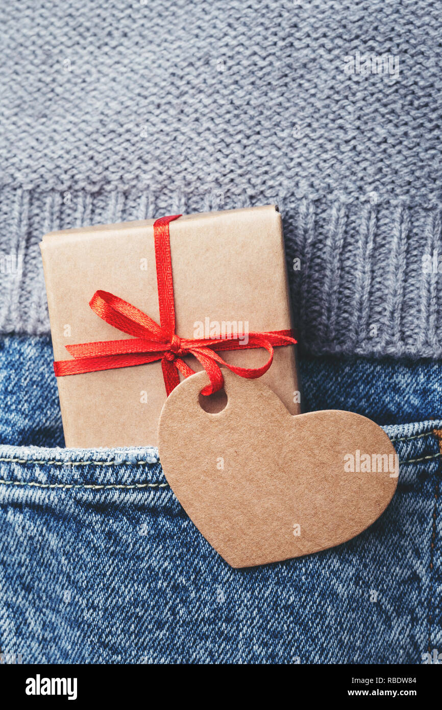 Kraft gift box with red bow and tag in shape of heart sticking out of ...