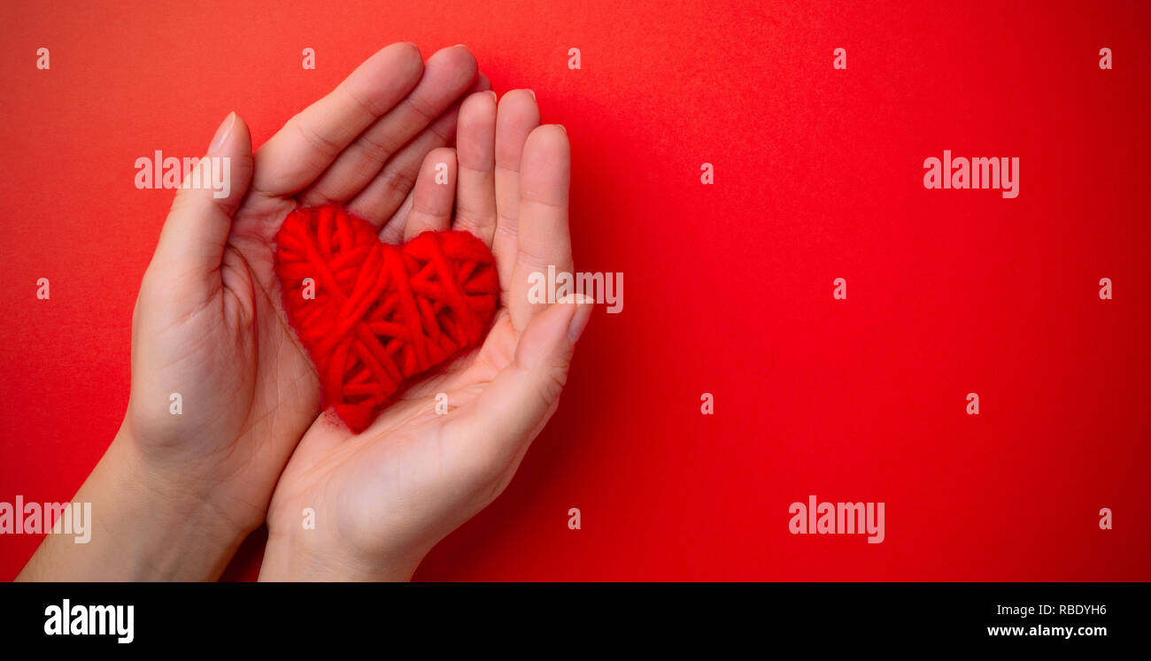 Hands hold red heart on red background Stock Photo - Alamy