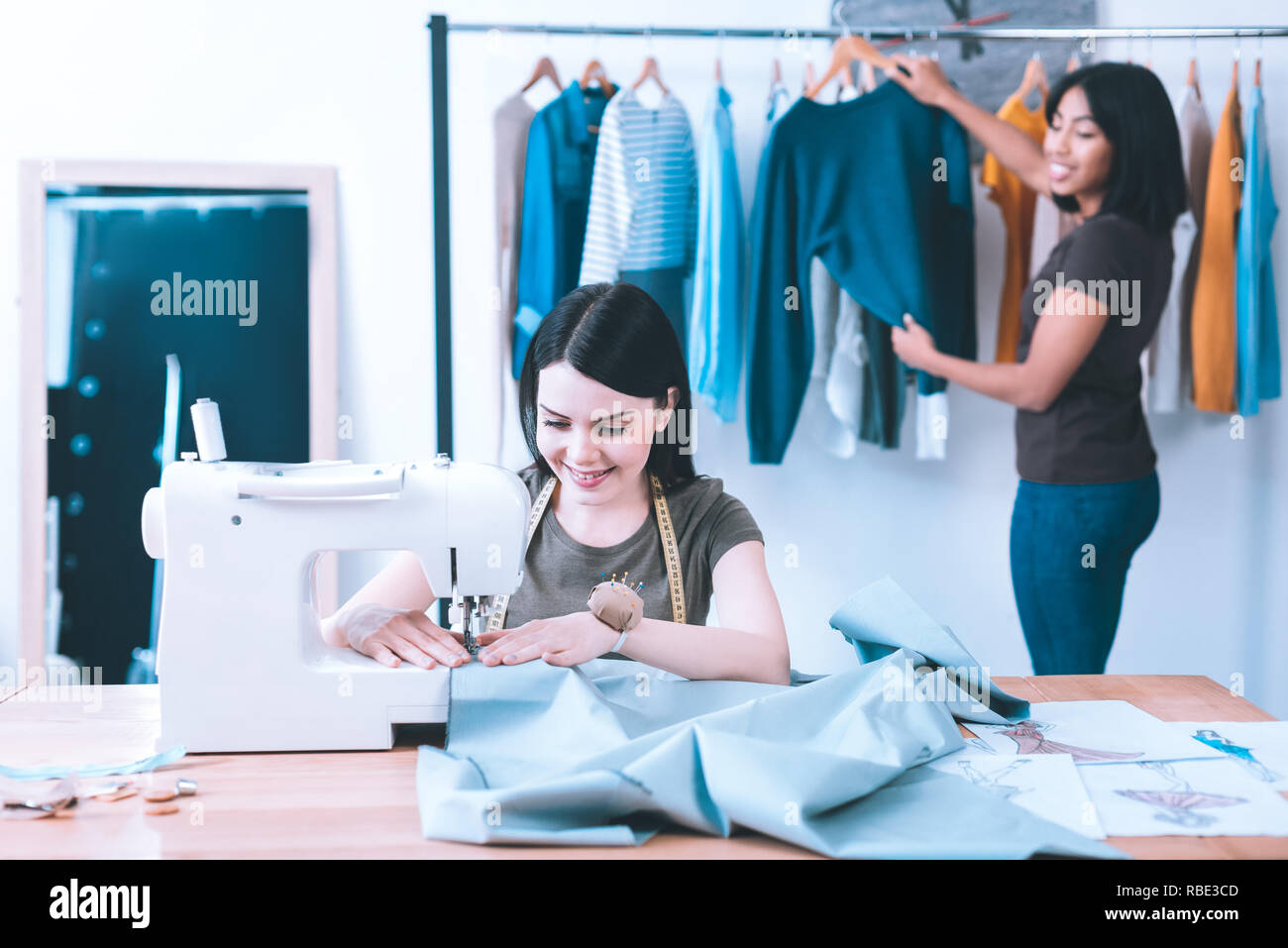 Favorite job. Smiling ingenious girl creating a clothes using sewing ...