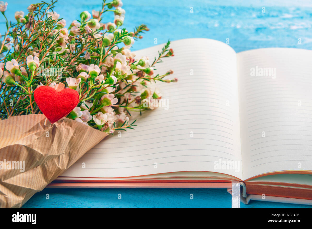 Bouquet of tiny white flowers on an open diary on a blue background ...