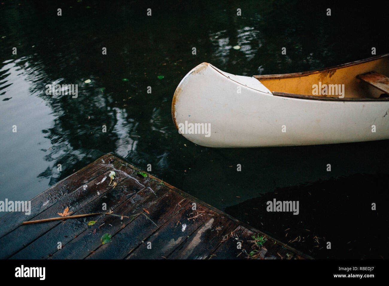empty canoe sitting near dock on water Stock Photo - Alamy