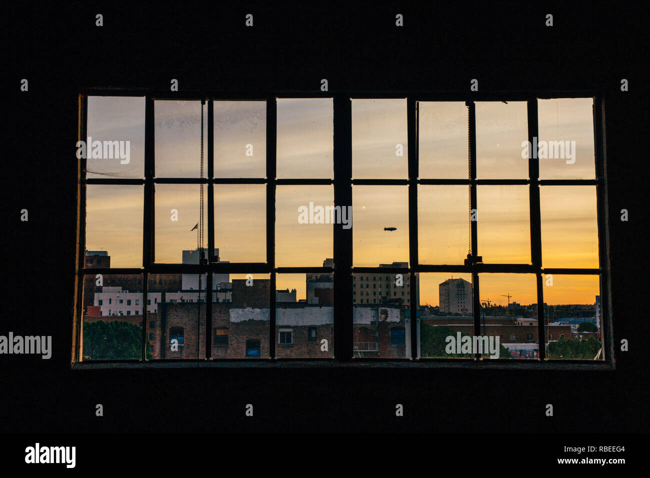 sunset through window pane with a cityscape and blimp Stock Photo - Alamy