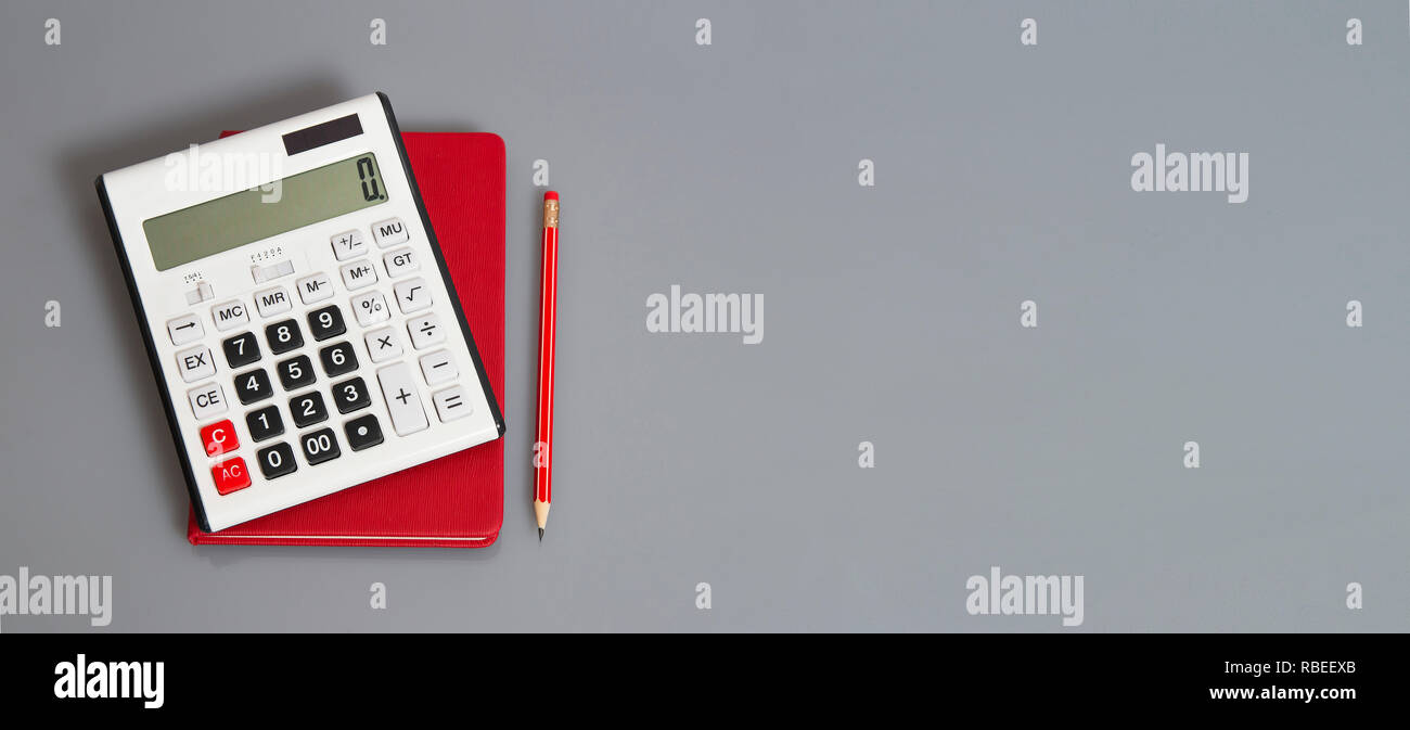 white calculator and red organizer on the grey table with red pencil ...