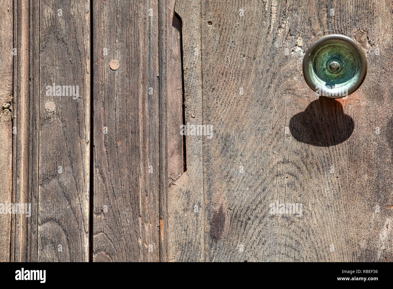 Closeup photo of a worn, brass door handle with a strong shadow on a ...