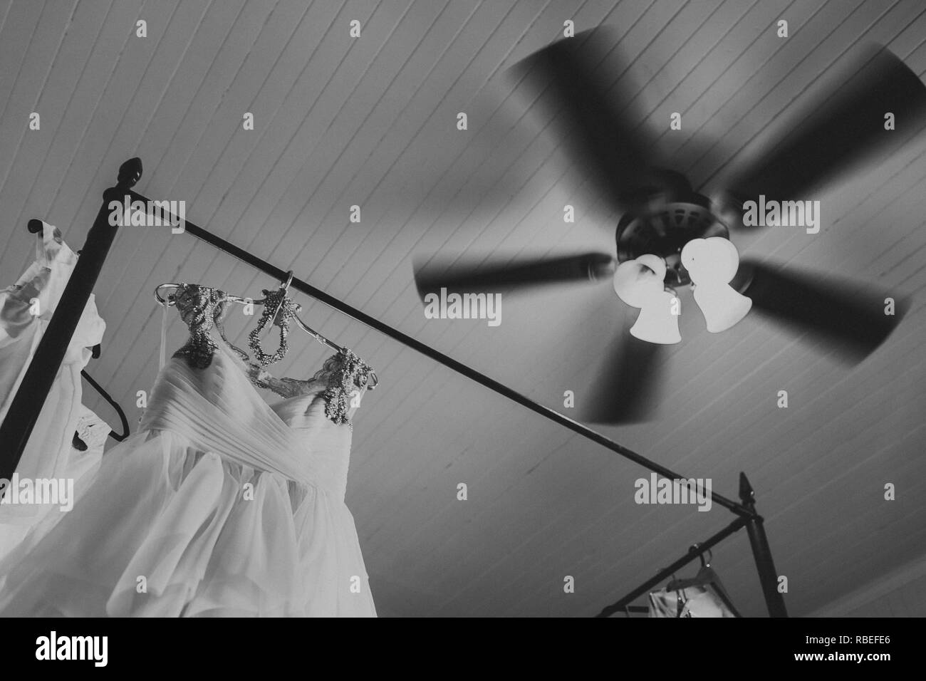 wedding dress hanging on rack near ceiling fan Stock Photo - Alamy