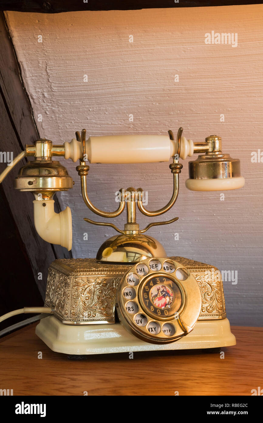 Close-up of antique 1800s ivory and gold rotary dial telephone on top ...