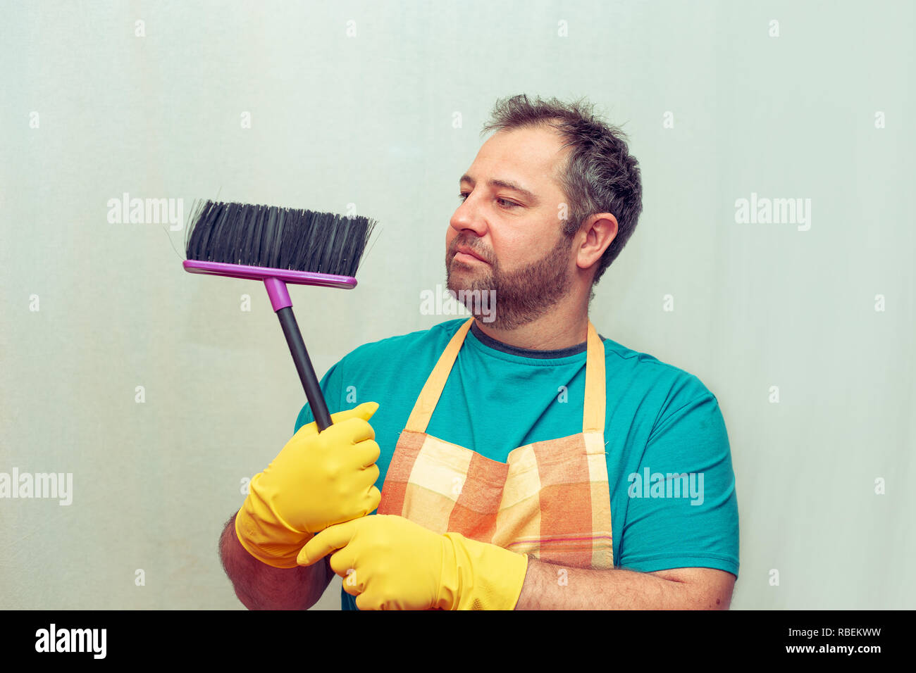 Emotional bearded man holding a broom. Light background Stock Photo - Alamy