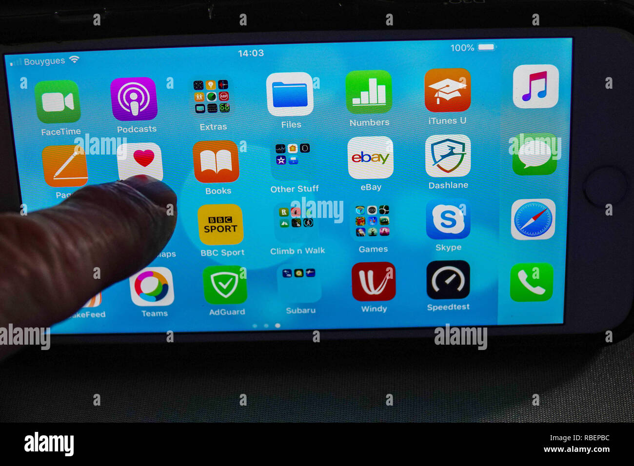 Apple iPhone 7+ screen with various icons showing and finger pointing ...