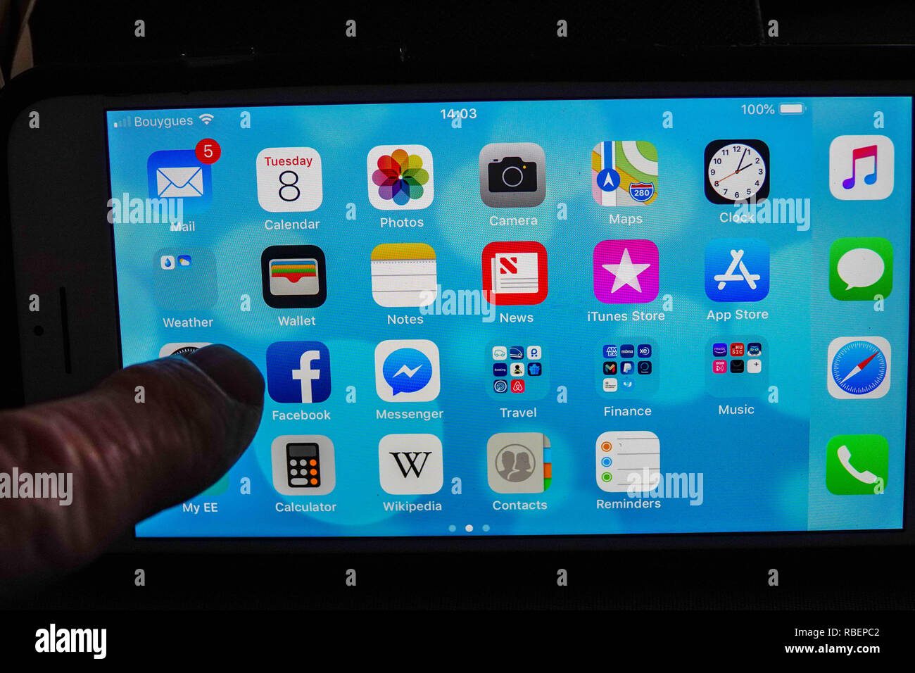Apple iPhone 7+ screen with various icons showing and finger pointing ...
