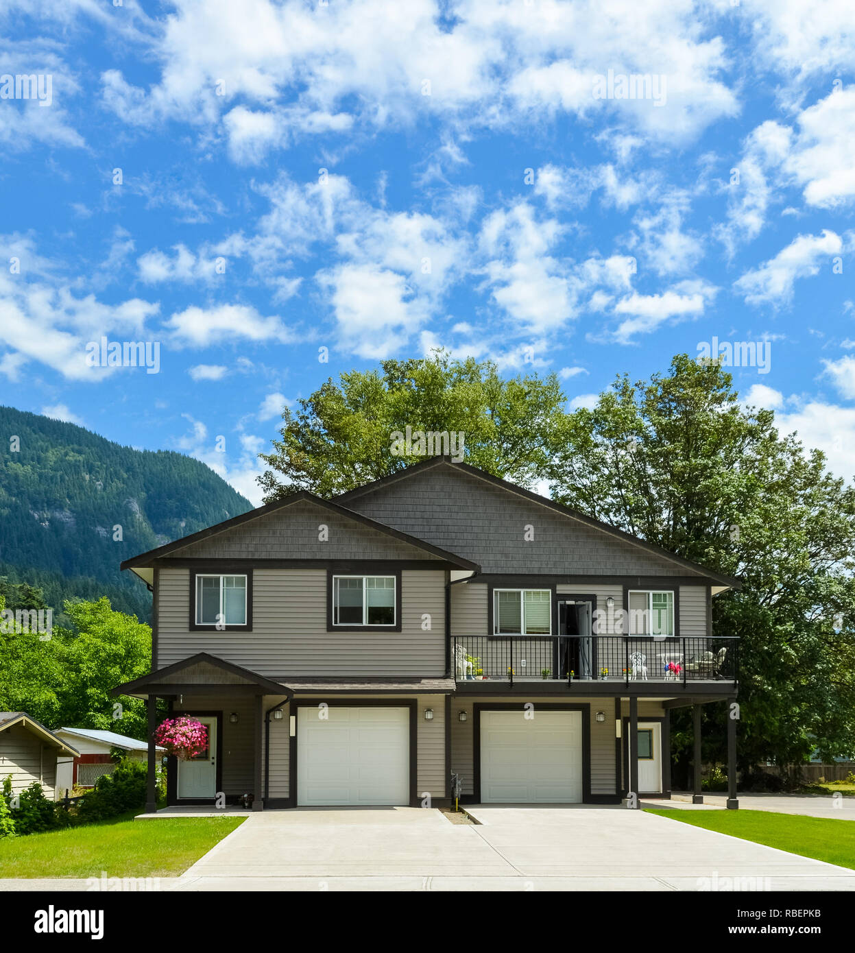 Modern residential duplex house with concrete driveway on cloudy sky ...