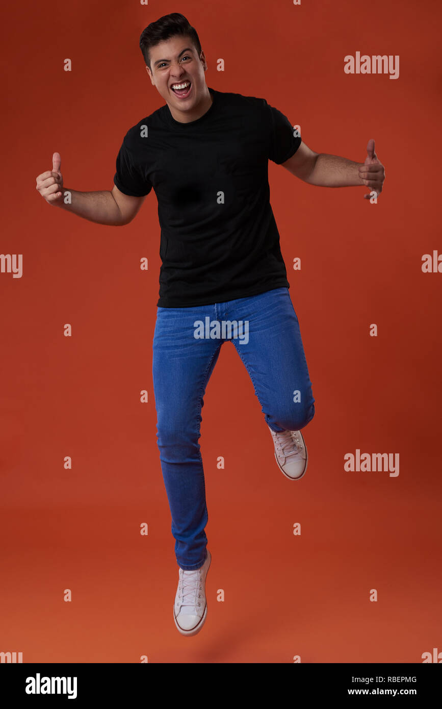 One young man jump in air on orange color studio background Stock Photo ...