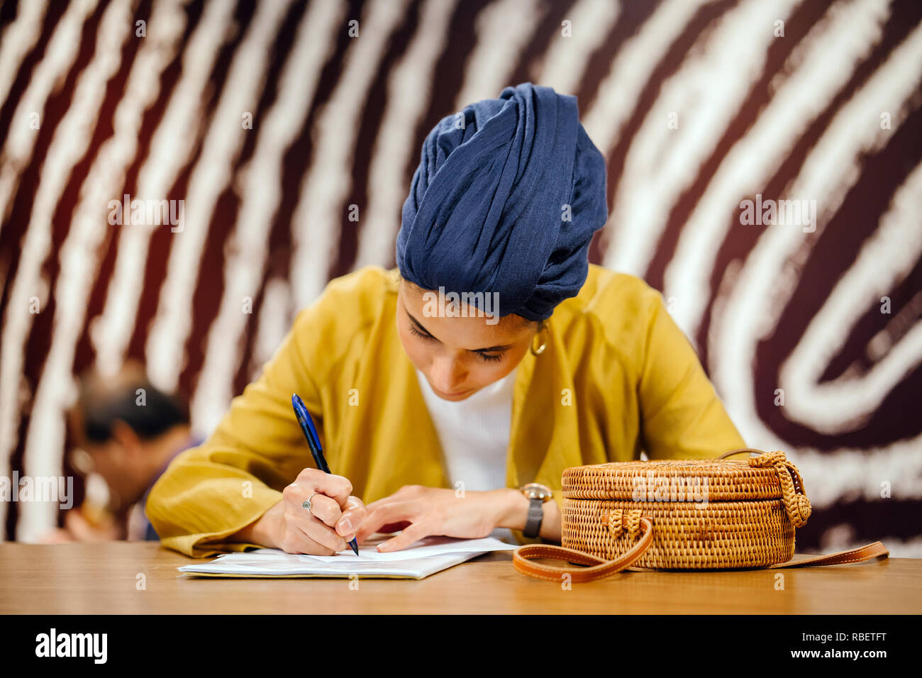 Portrait of a beautiful and elegant Middle Eastern woman writing in her ...