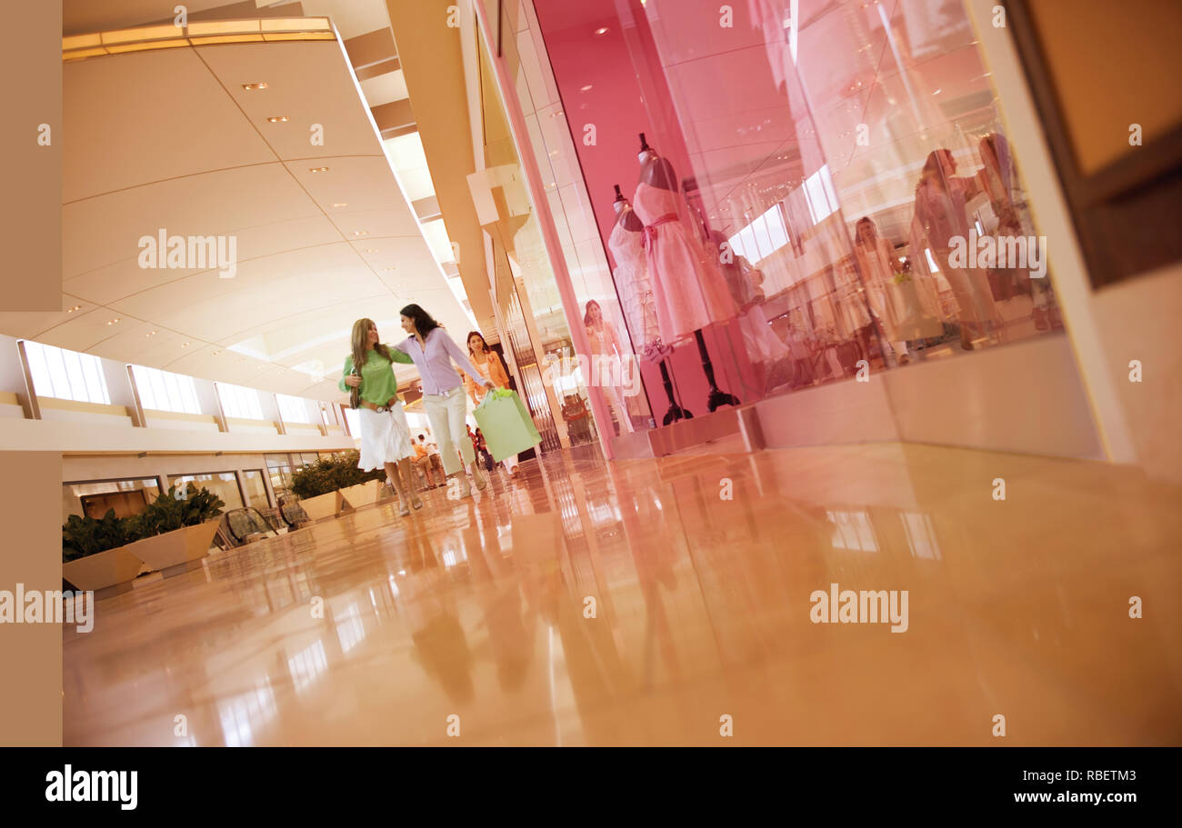 Smiling friends walking through a shopping mall Stock Photo - Alamy