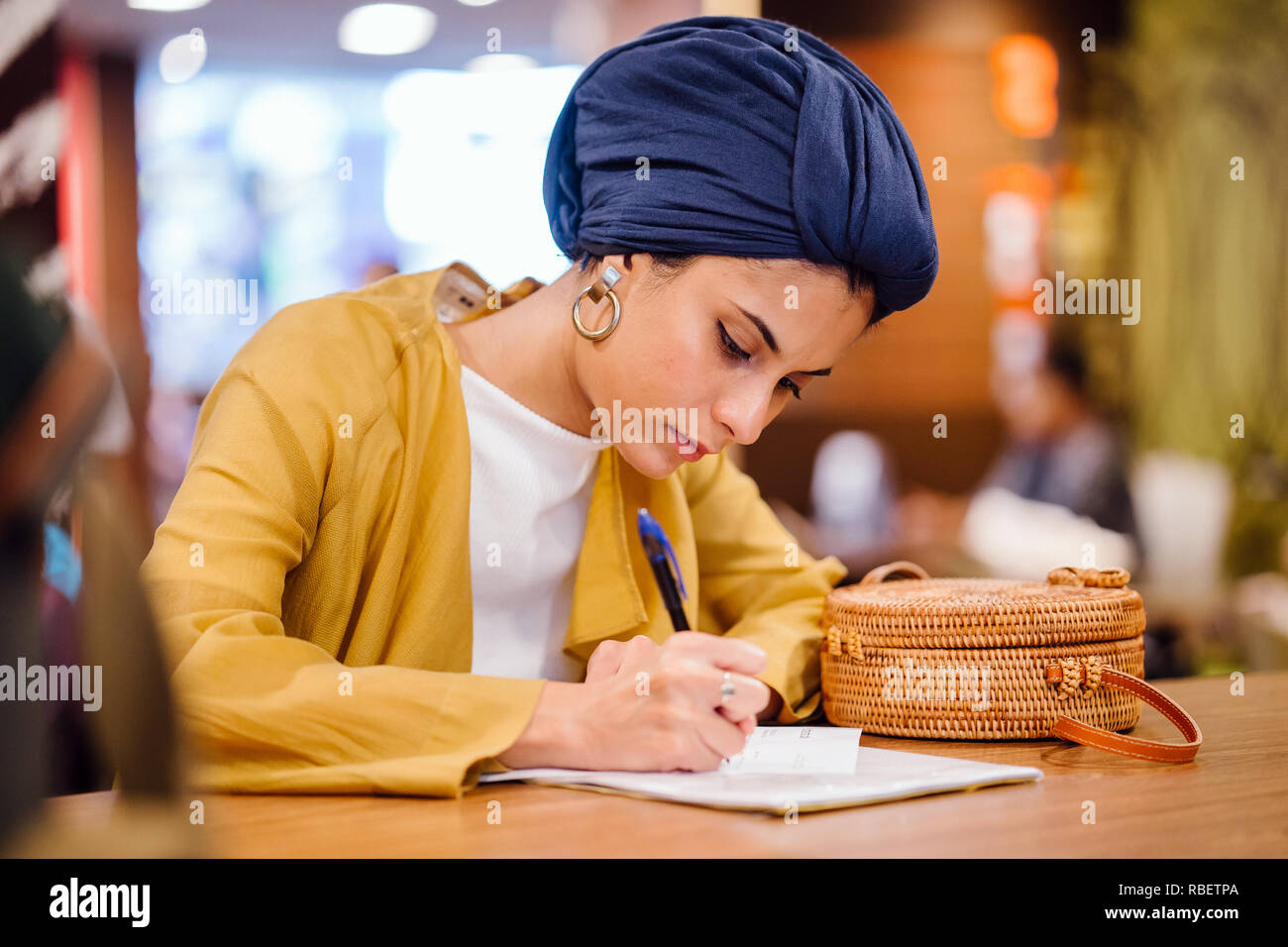 Portrait of a beautiful and elegant Middle Eastern woman writing in her ...