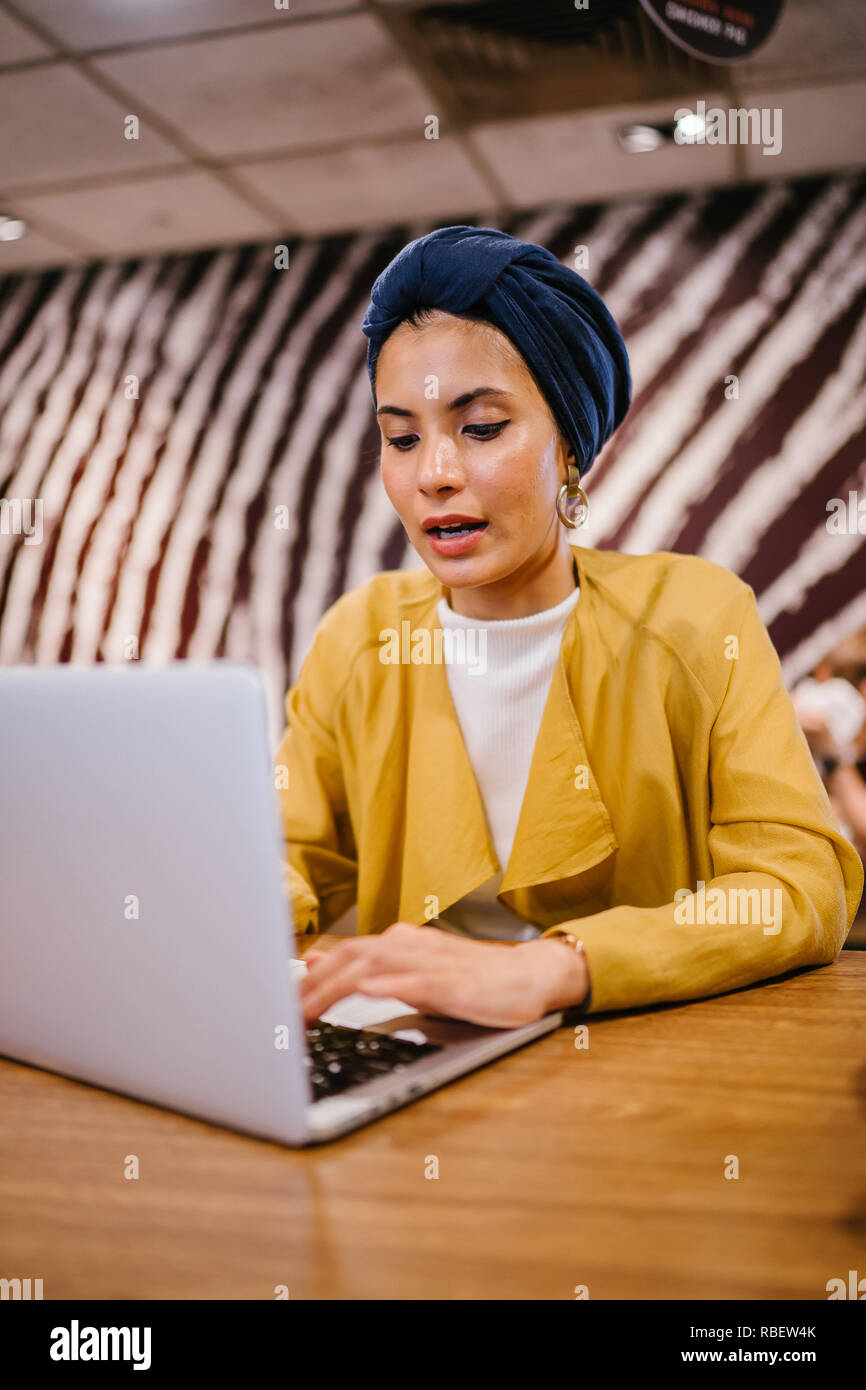 A young Malay Asian woman is typing and working or studying on her ...