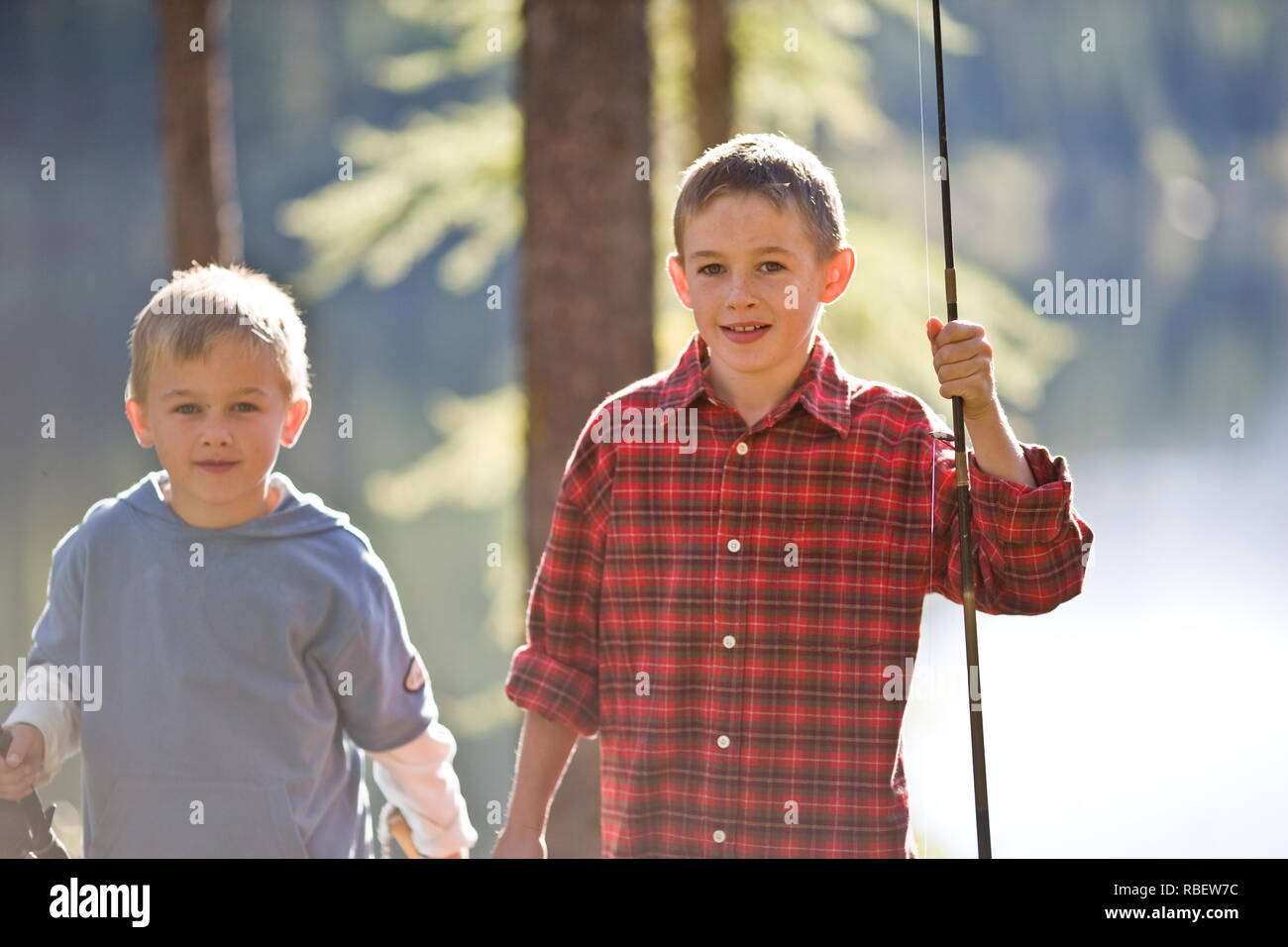 Portrait of two young brothers holding fishing rods while out in the ...
