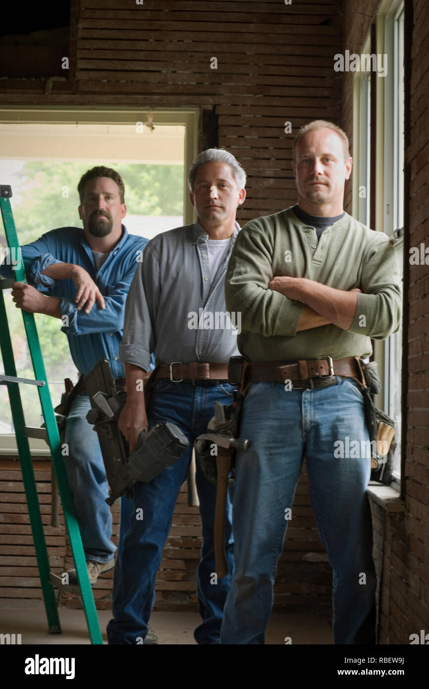 Portrait of three male builders standing inside a room they are working ...