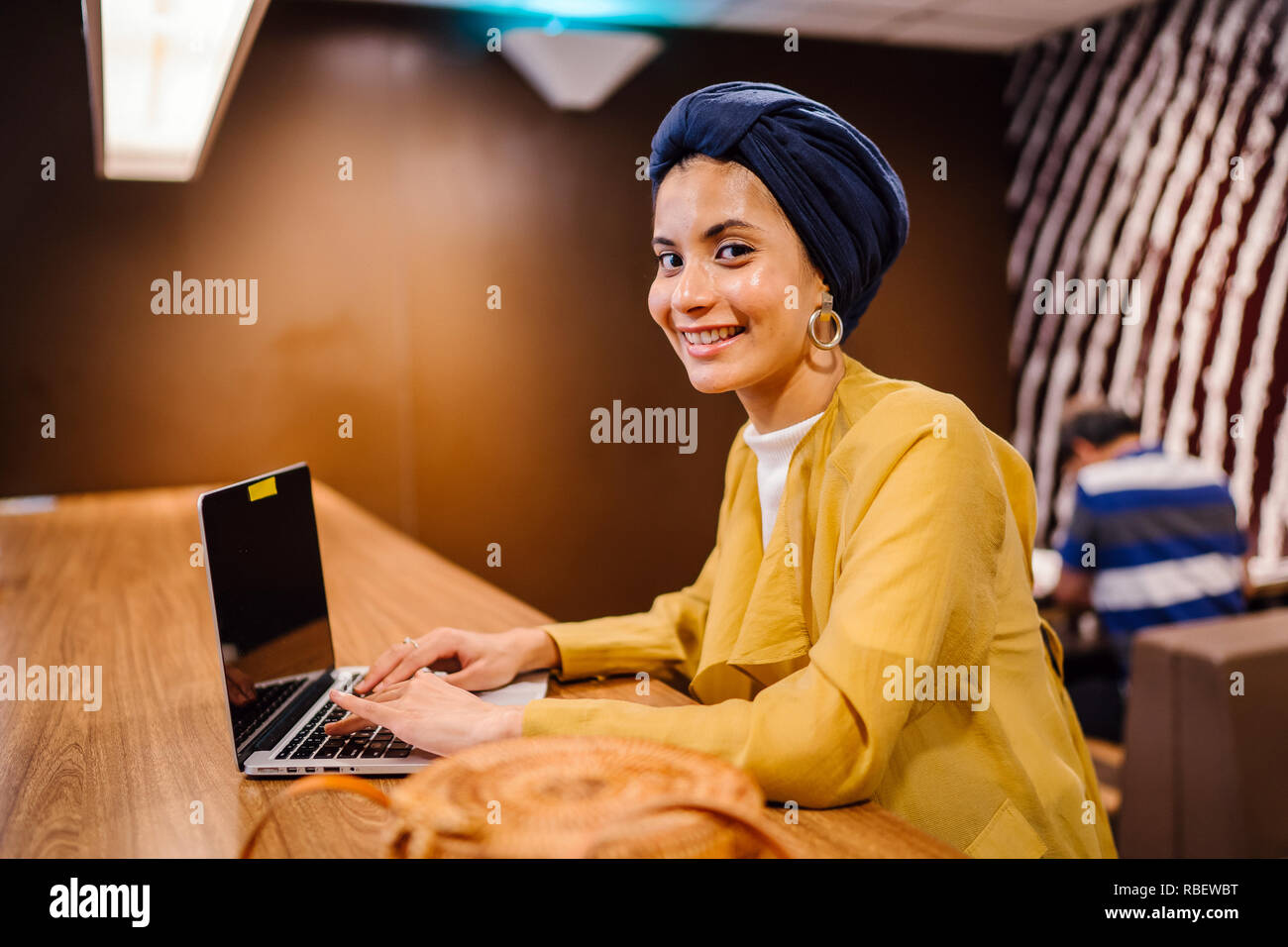 A young Malay Asian woman is typing and working or studying on her ...