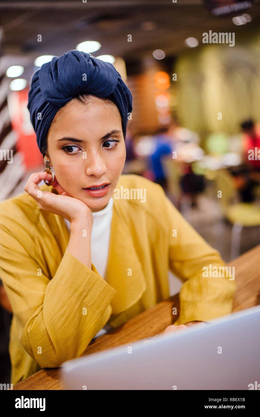 A young Malay Asian woman is typing and working or studying on her ...