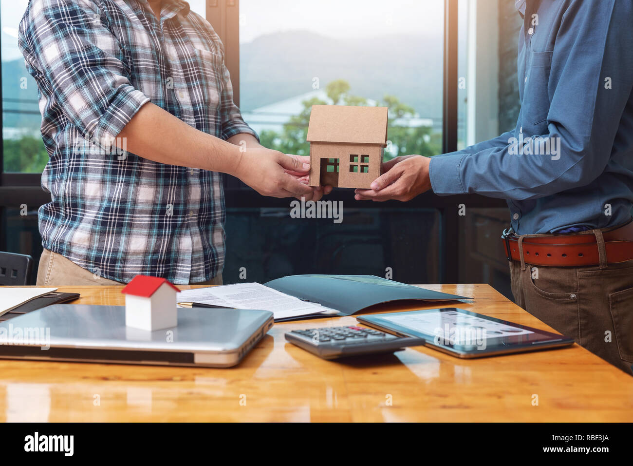 Real estate agent handing over a house model with his client after ... Real estate agent handing over a house model with his client after ...